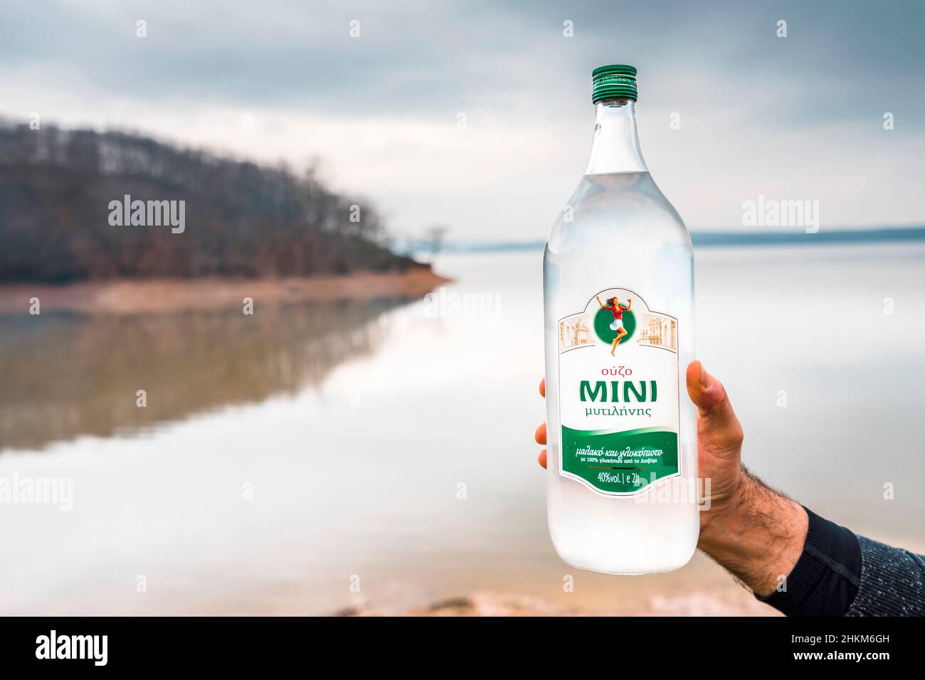 Hand of male holding two liter bottle of Greek anise alcoholic beverage ...