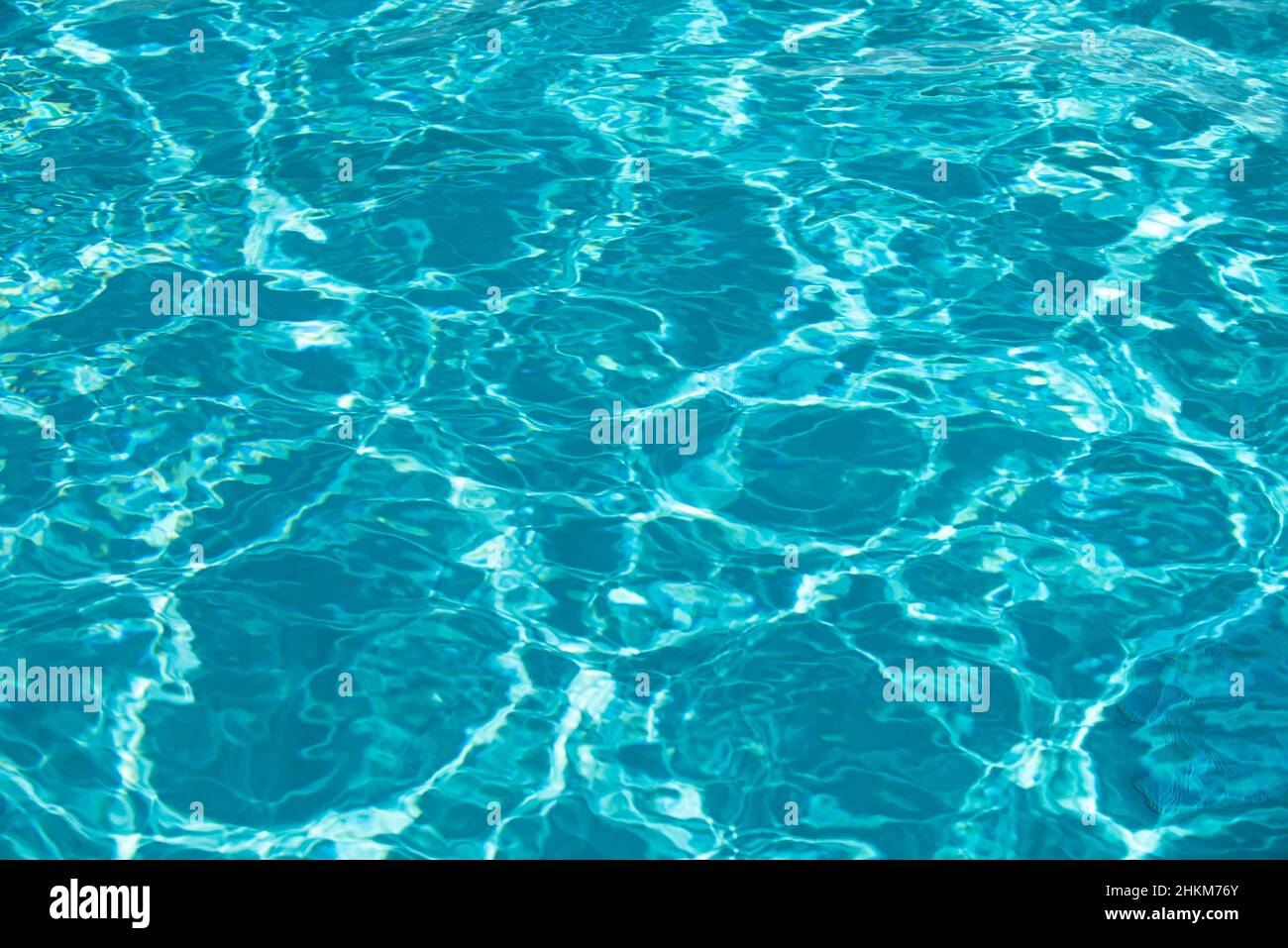 Background of blue water in swimming pool with sun reflection, ripple water wave in pool. Clear ...