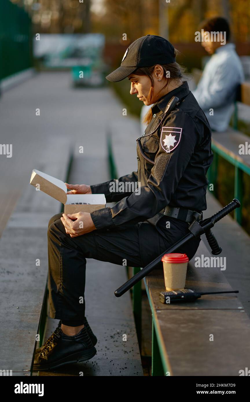Police officer eating donut in park closeup Stock Photo - Alamy