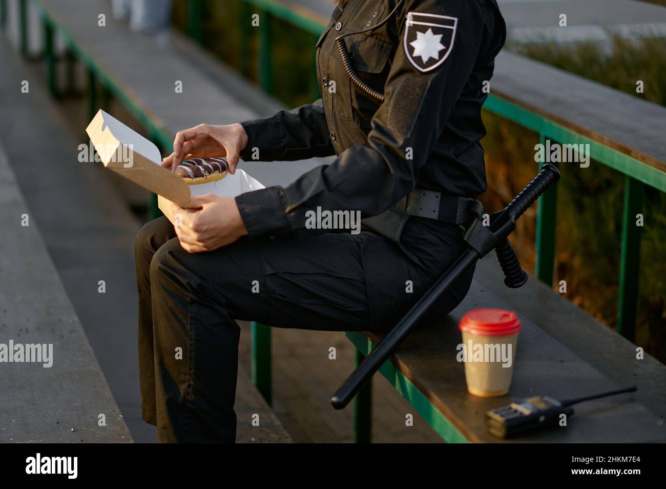 Police officer eating donut in park closeup Stock Photo - Alamy