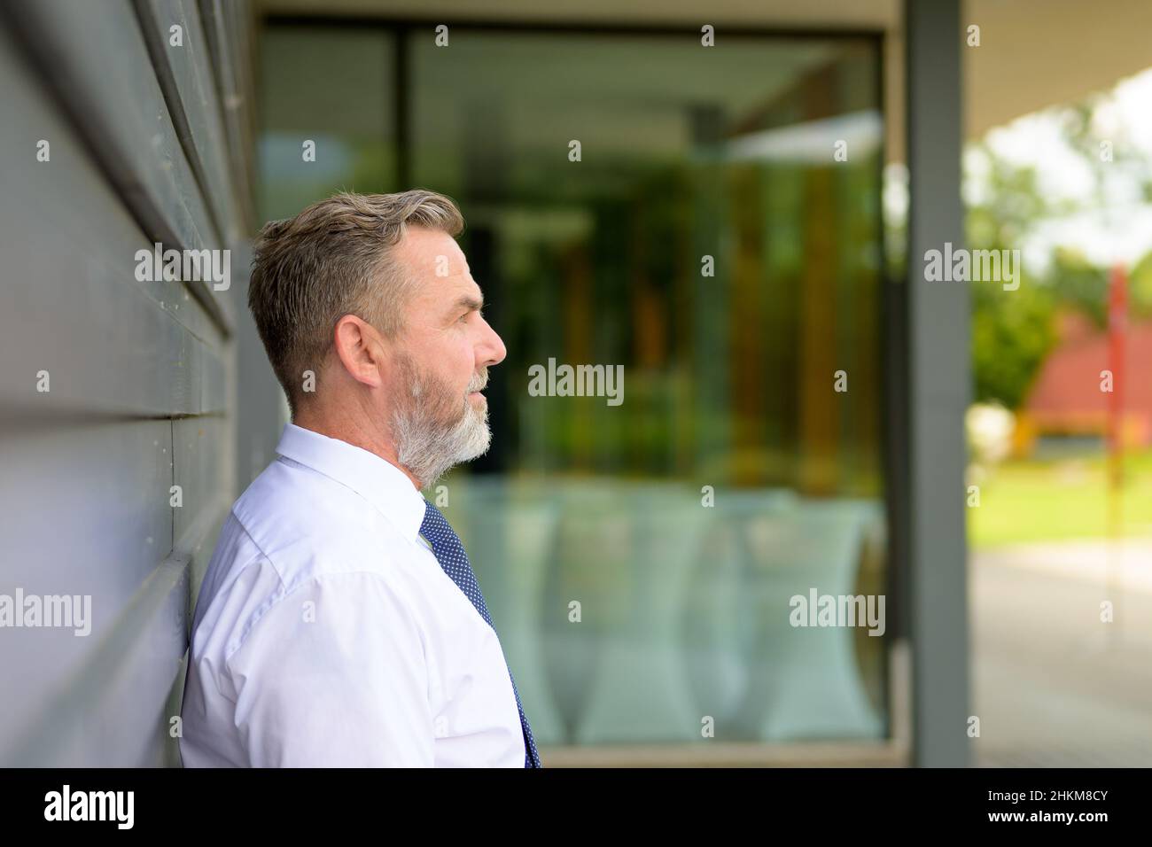 Side view portrait of a senior man standing waiting in town with his ...