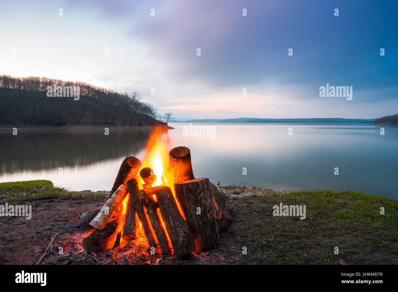Big campfire with flames beside a lake during a winter sunset Stock ...