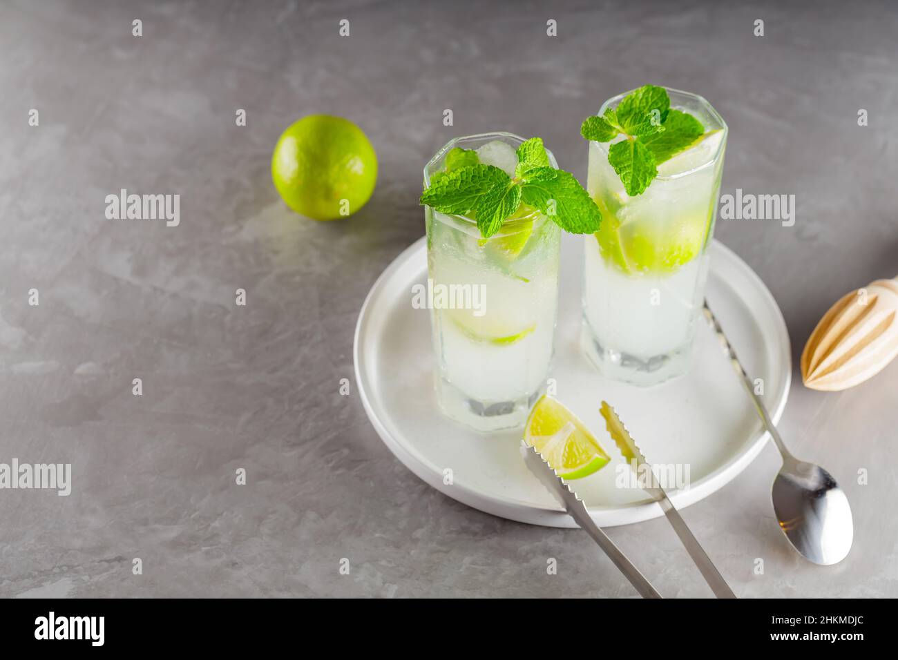 Mojito cocktail and bar accessories on gray background. Two highball ...