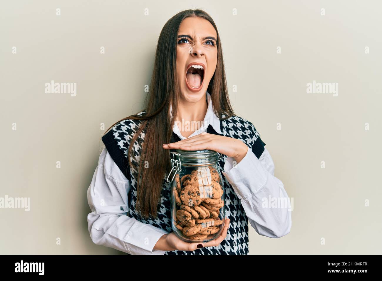 Beautiful brunette young woman holding jar of chocolate chips cookies ...