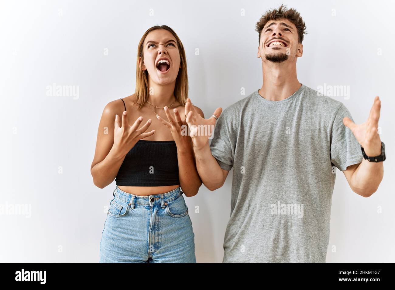 Young beautiful couple standing together over isolated background crazy ...