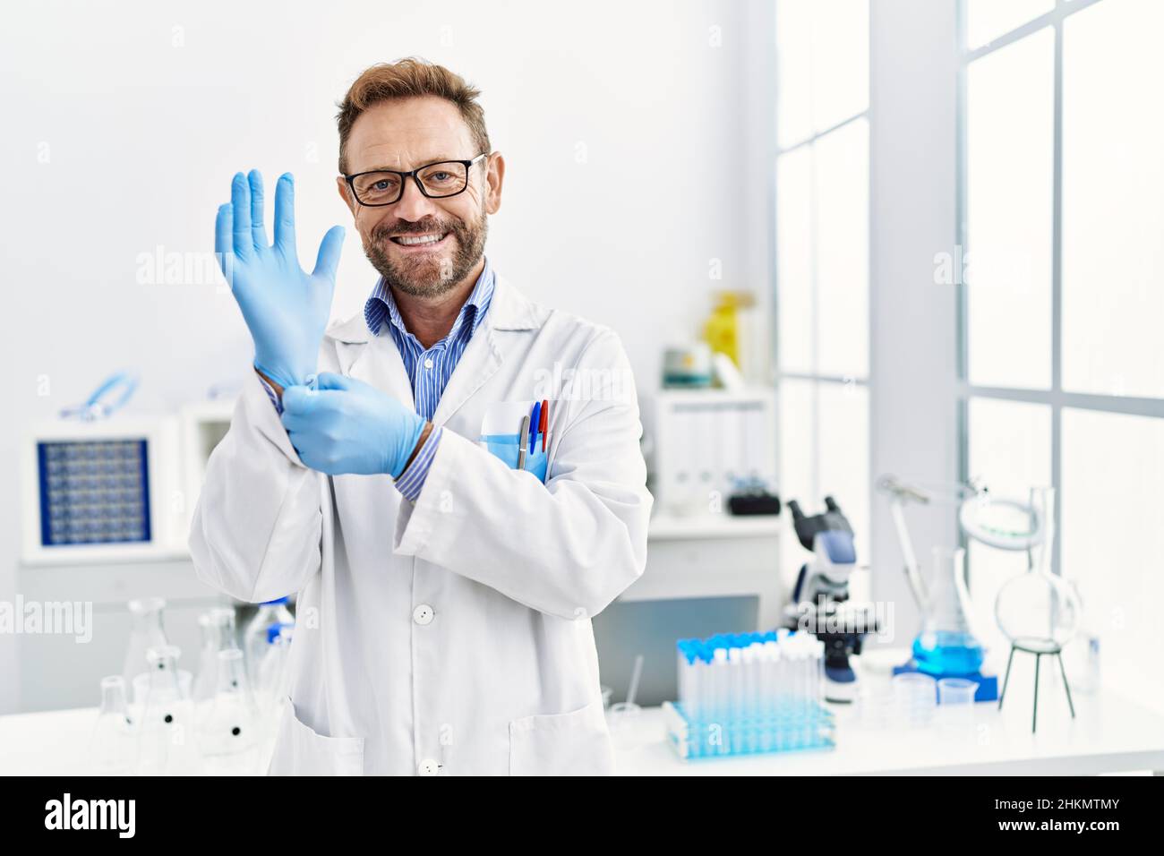 Middle age man working at scientist laboratory smiling with a happy and ...