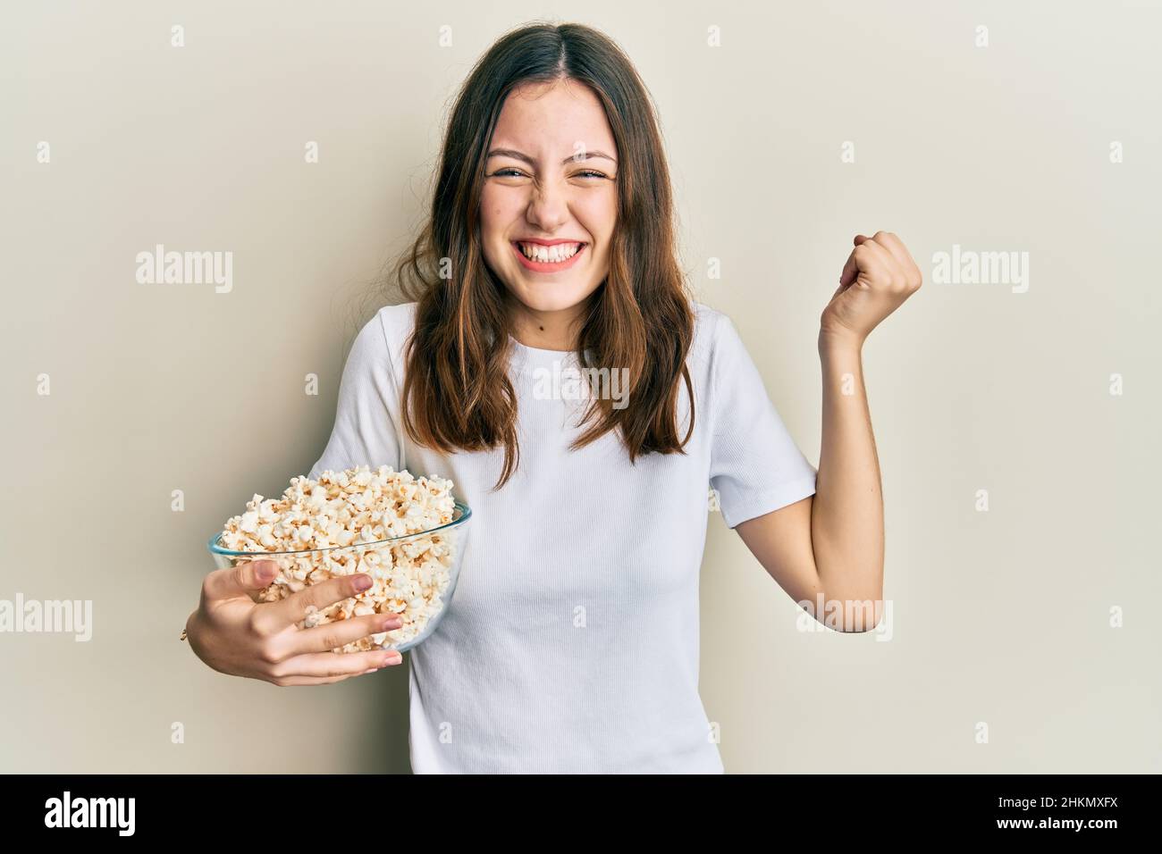 Young brunette woman eating popcorn screaming proud, celebrating ...