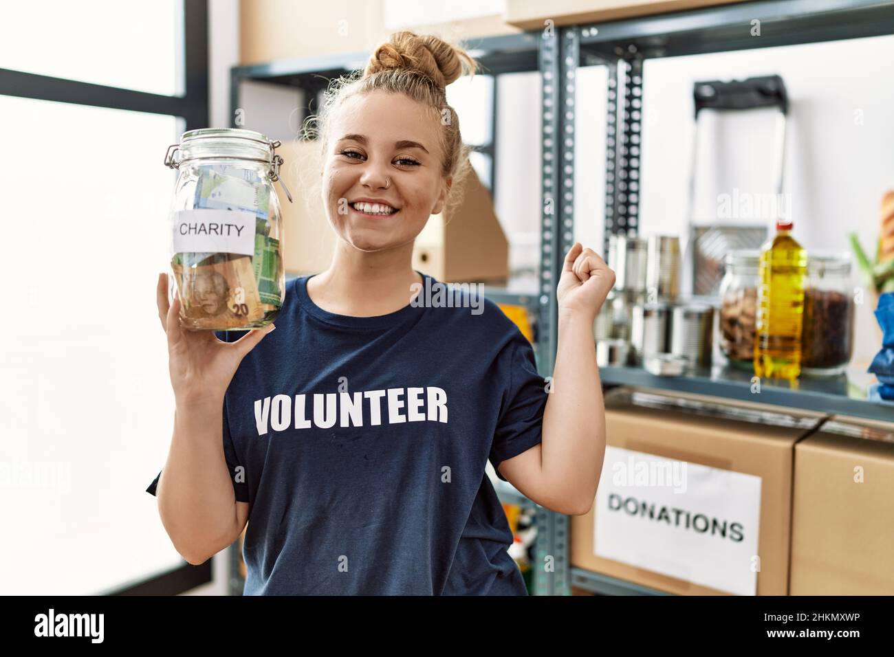 Young caucasian woman holding charity jar with money at donations stand ...
