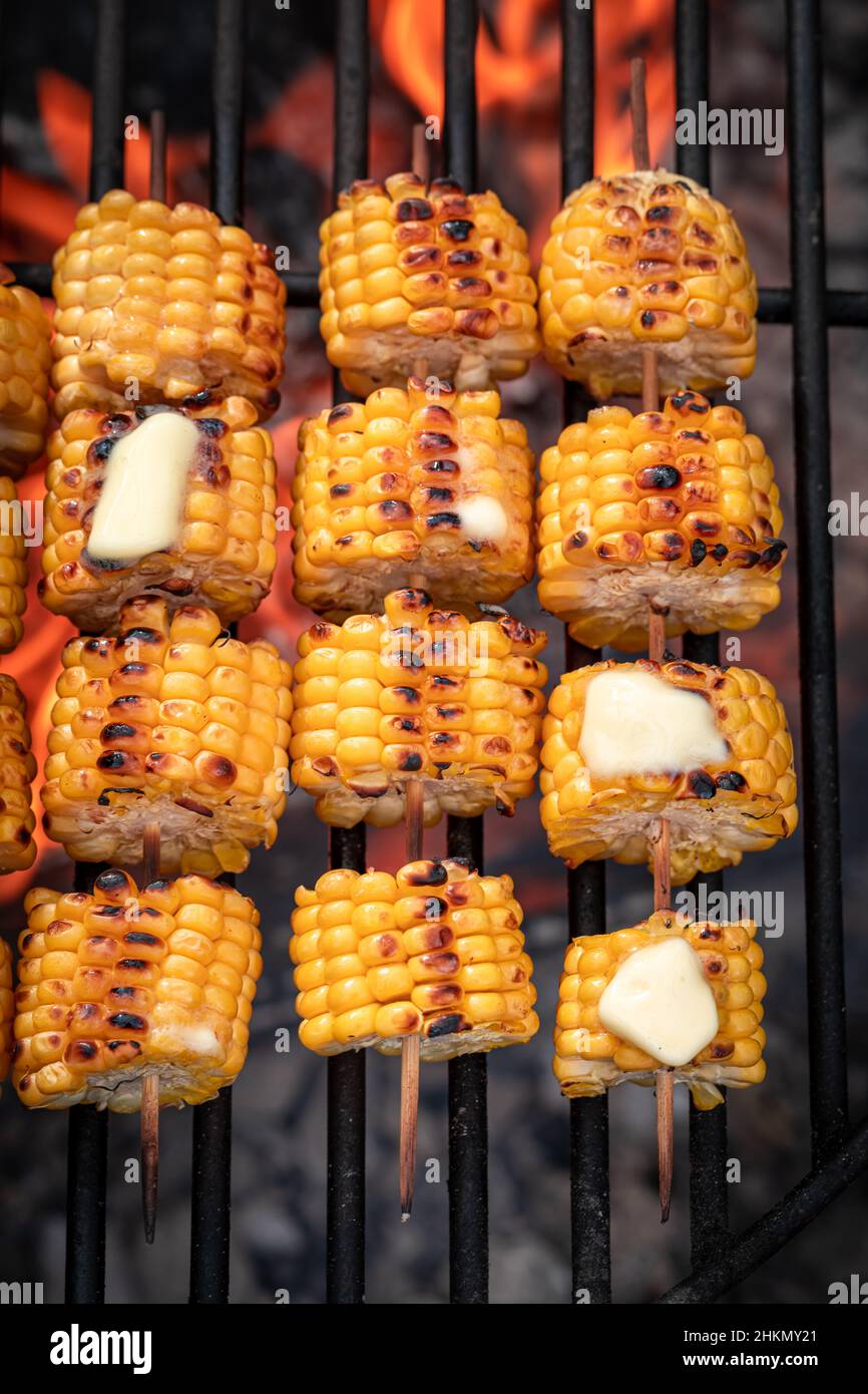 Hot corncob on grill with melting butter on fire. Grill with fire and ...