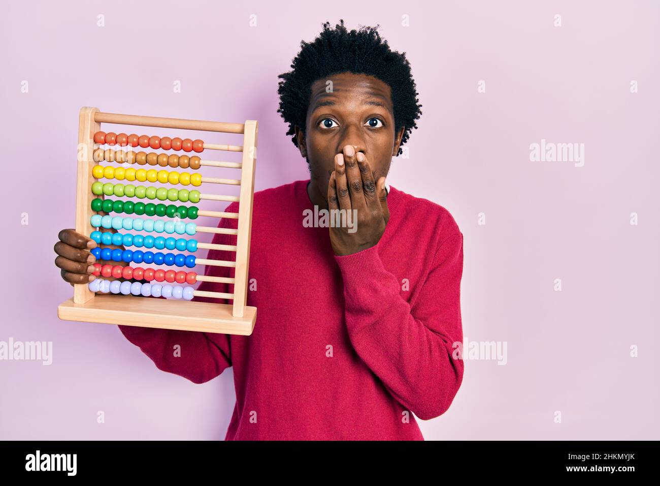 Young african american man holding traditional abacus covering mouth ...