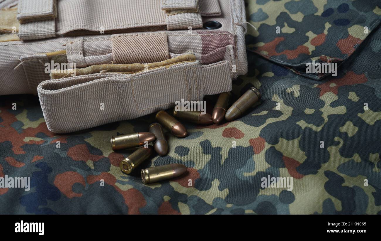 Ammunition and handgun holster on a camouflage background. Nine ...