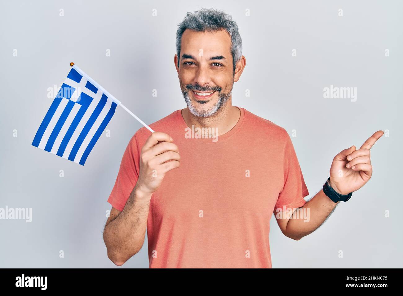 Handsome middle age man with grey hair holding greece flag smiling ...