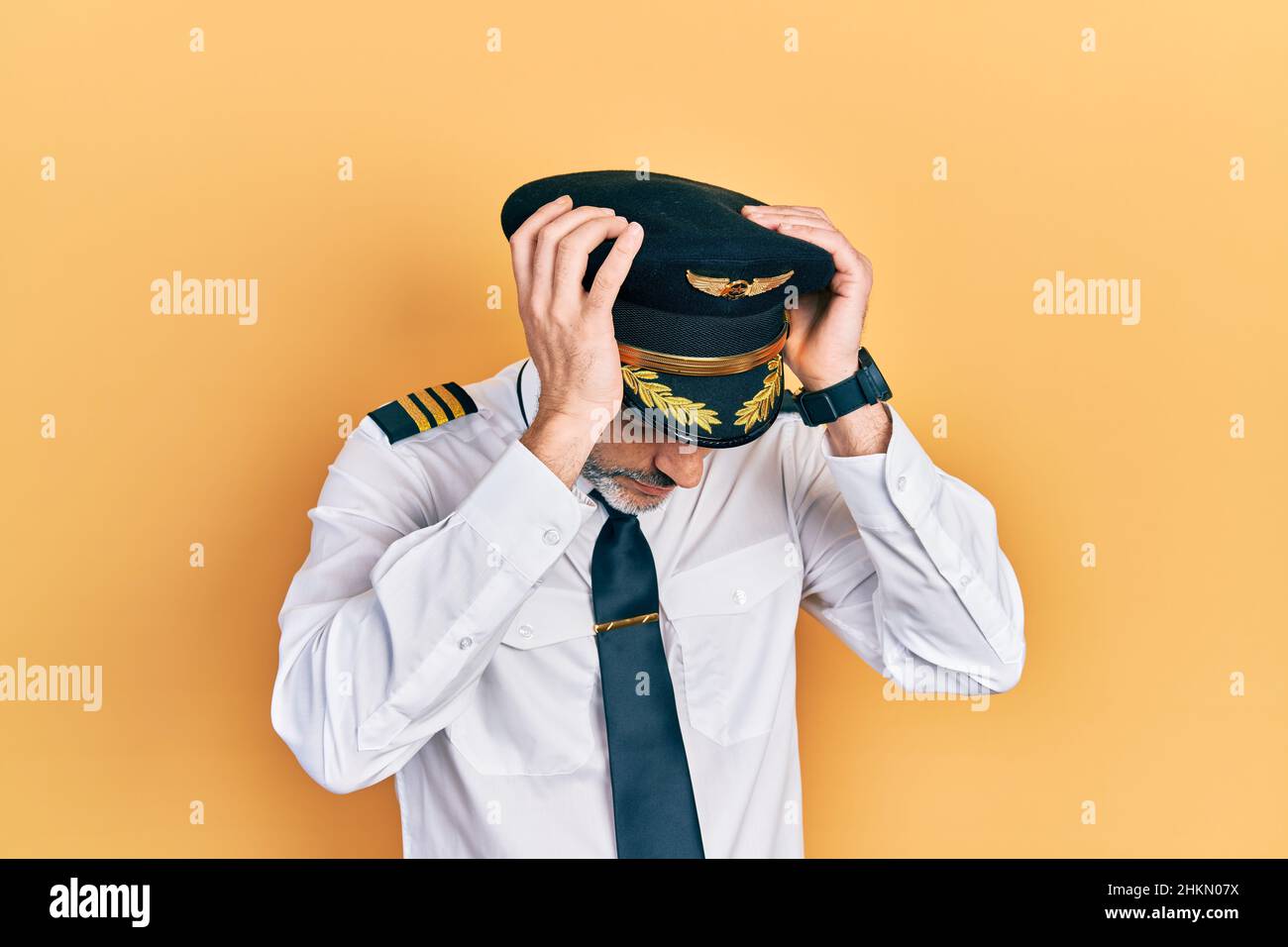 Handsome middle age man with grey hair wearing airplane pilot uniform ...