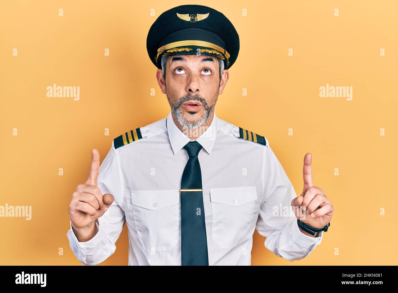 Handsome middle age man with grey hair wearing airplane pilot uniform ...