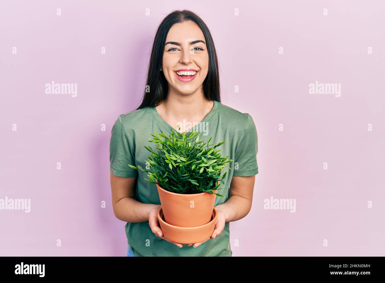 Beautiful woman with blue eyes holding green plant pot smiling and ...