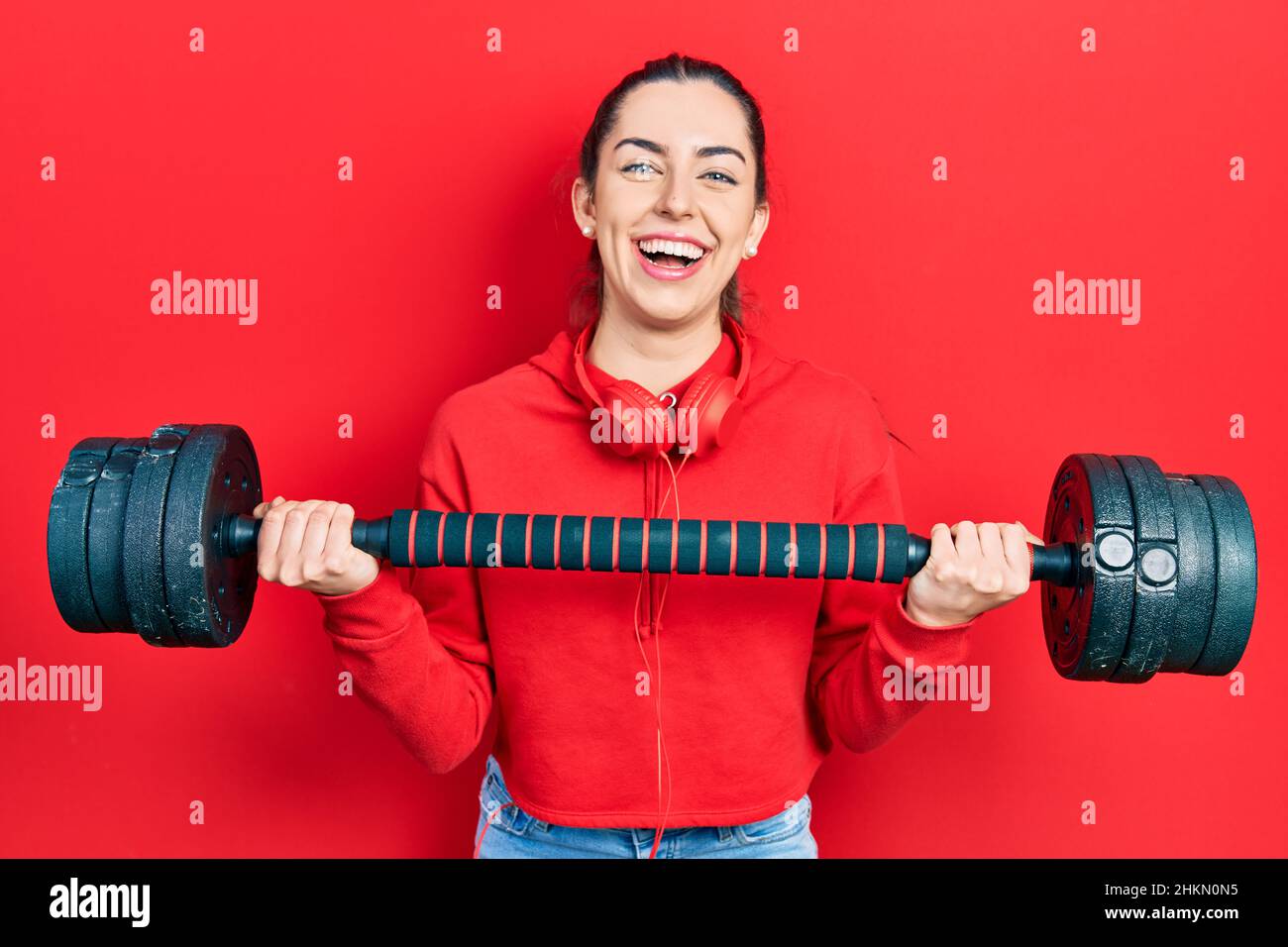 Beautiful woman with blue eyes wearing sportswear using dumbbells ...