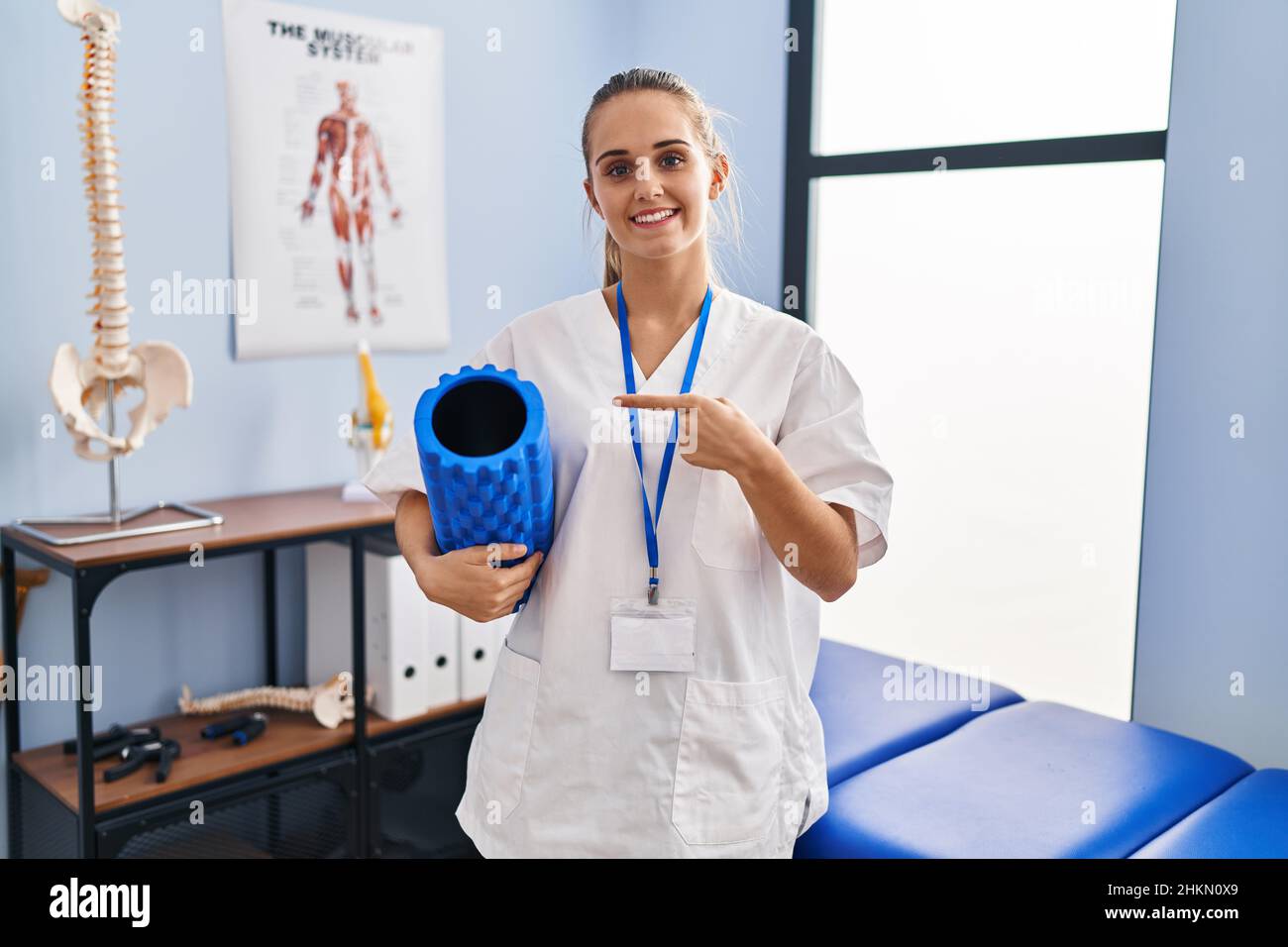 Young physiotherapist woman holding foam roll at the clinic smiling ...