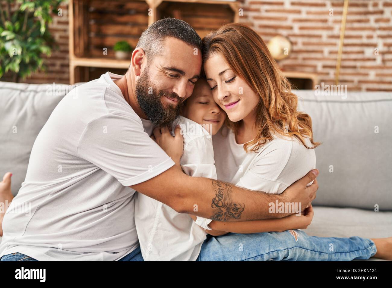 Family hugging each other sitting on sofa at home Stock Photo - Alamy