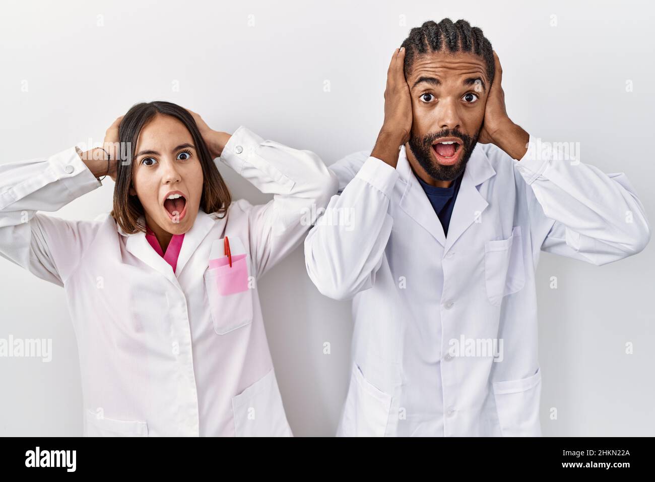 Young hispanic doctors standing over white background crazy and scared ...