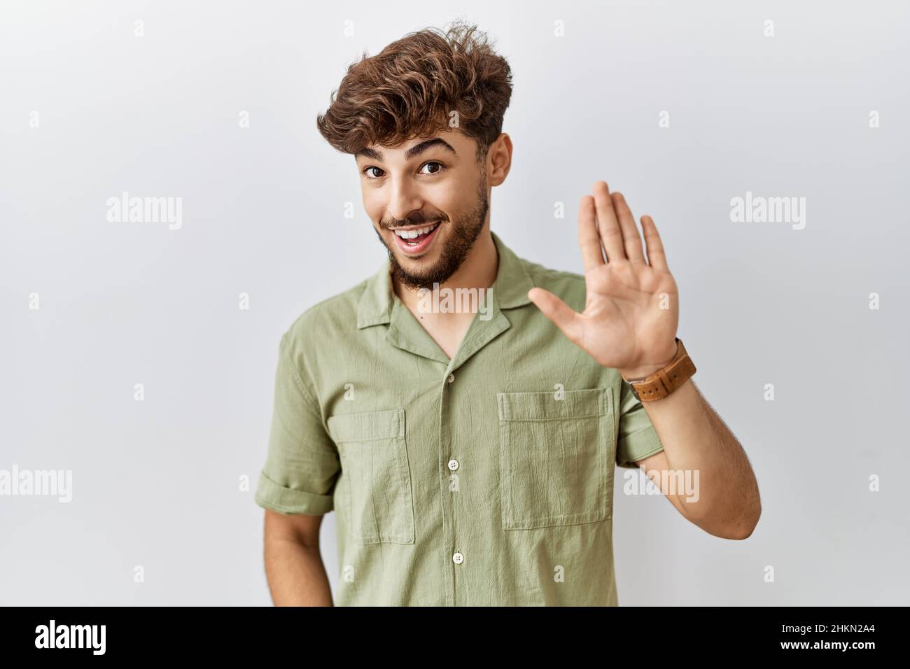 Young arab doctor man standing over isolated background waiving saying ...