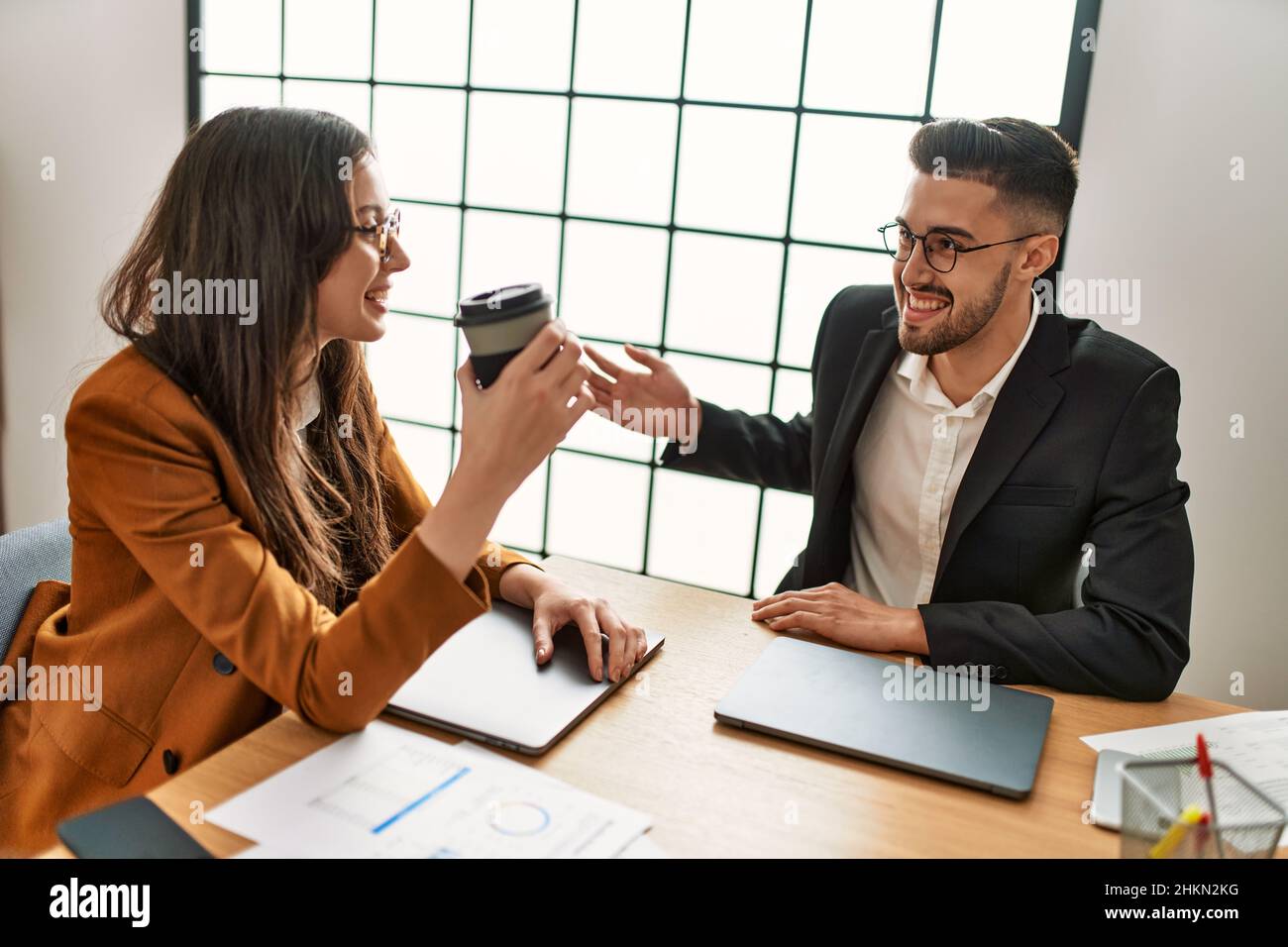 Two hispanic business workers smiling happy drinking coffee at the ...