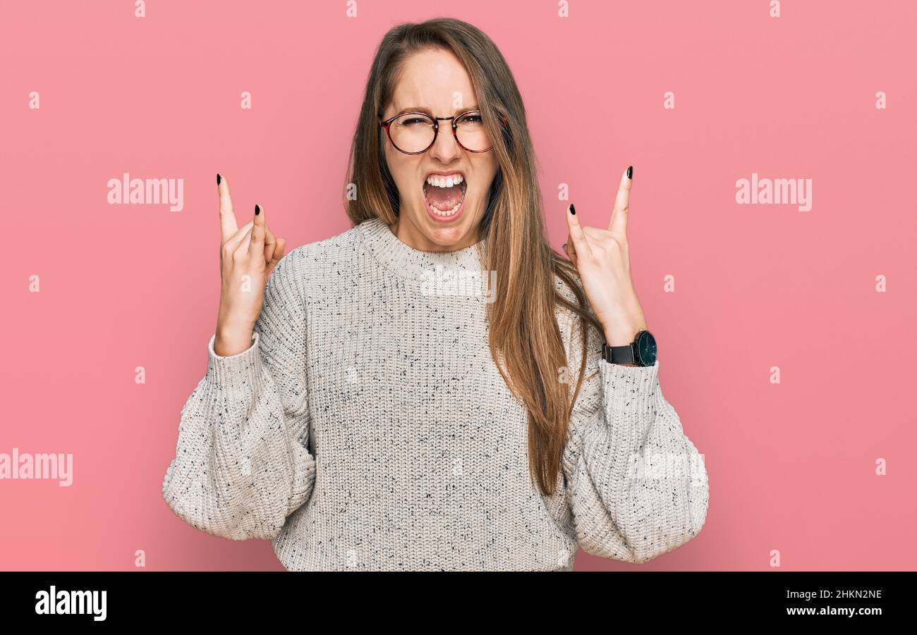 Young blonde woman wearing casual sweater and glasses shouting with ...