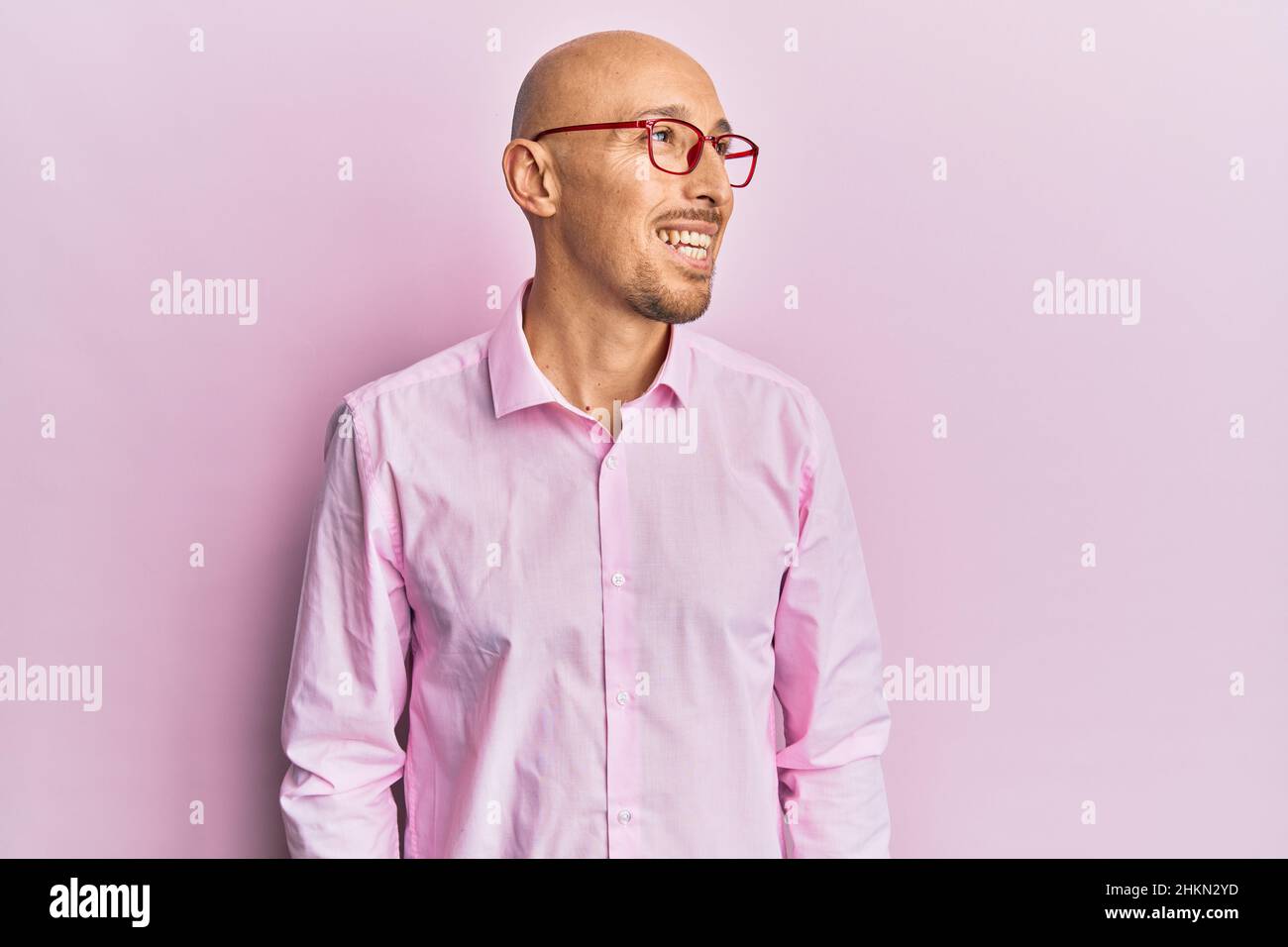 Bald man with beard wearing casual clothes and glasses looking to side ...