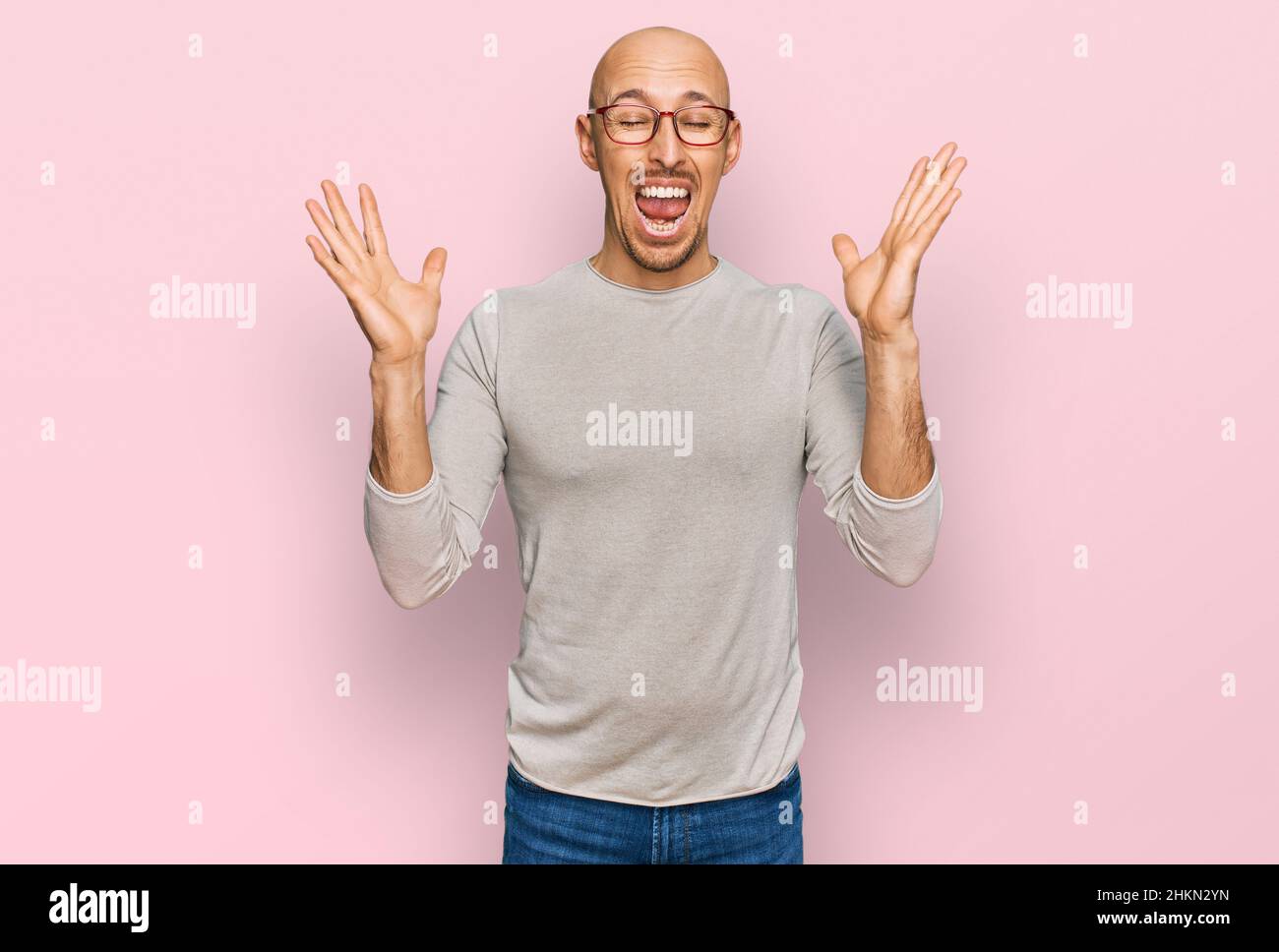 Bald man with beard wearing casual clothes and glasses celebrating mad ...