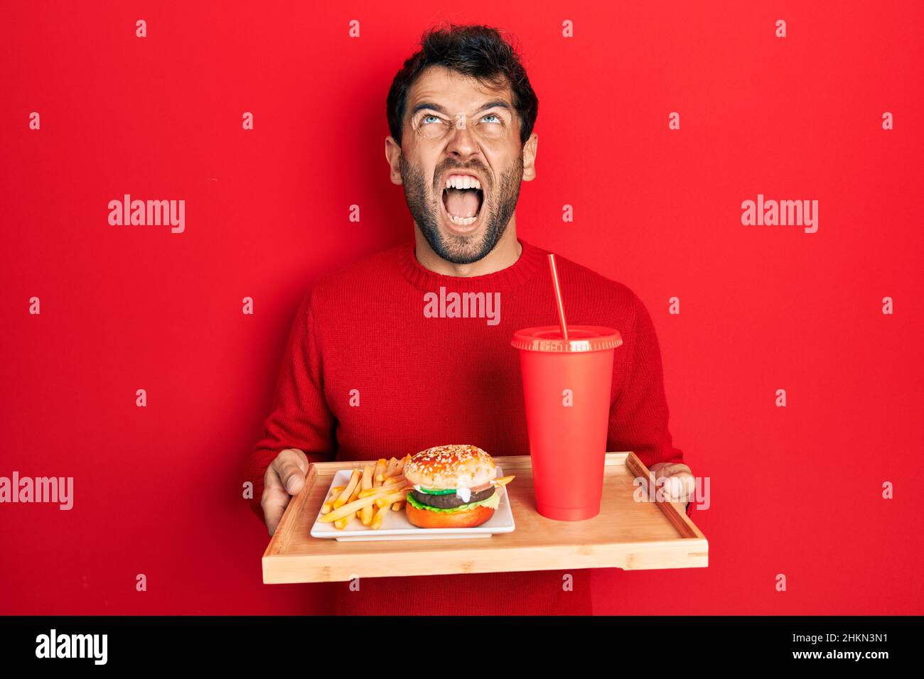 Handsome man with beard eating a tasty classic burger with fries and ...