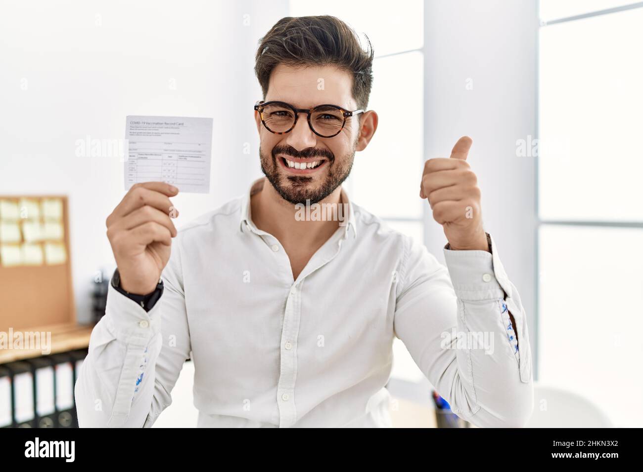 Young man with beard holding covid record card smiling happy and ...