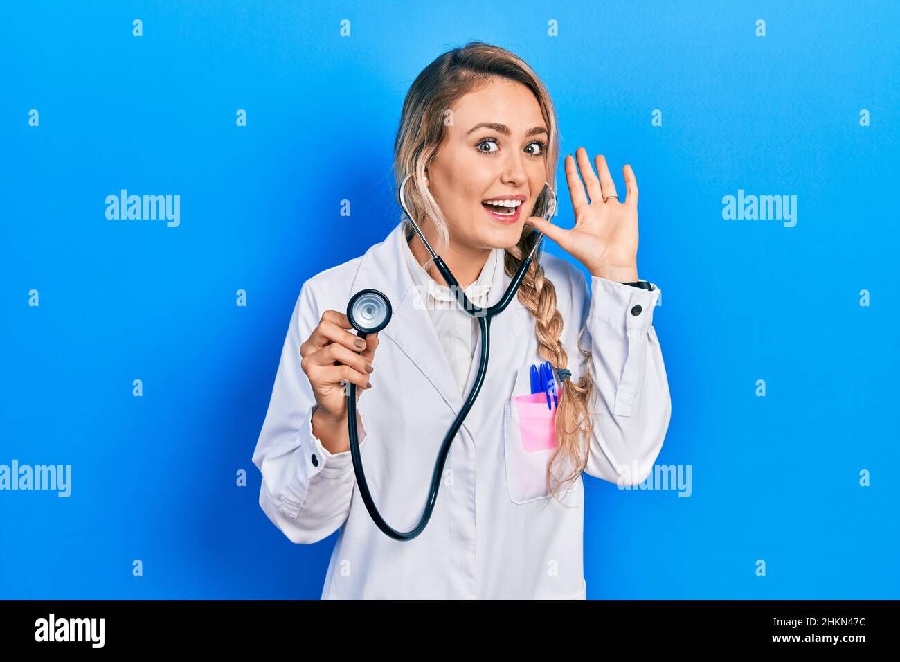 Beautiful young blonde doctor woman holding stethoscope smiling with ...