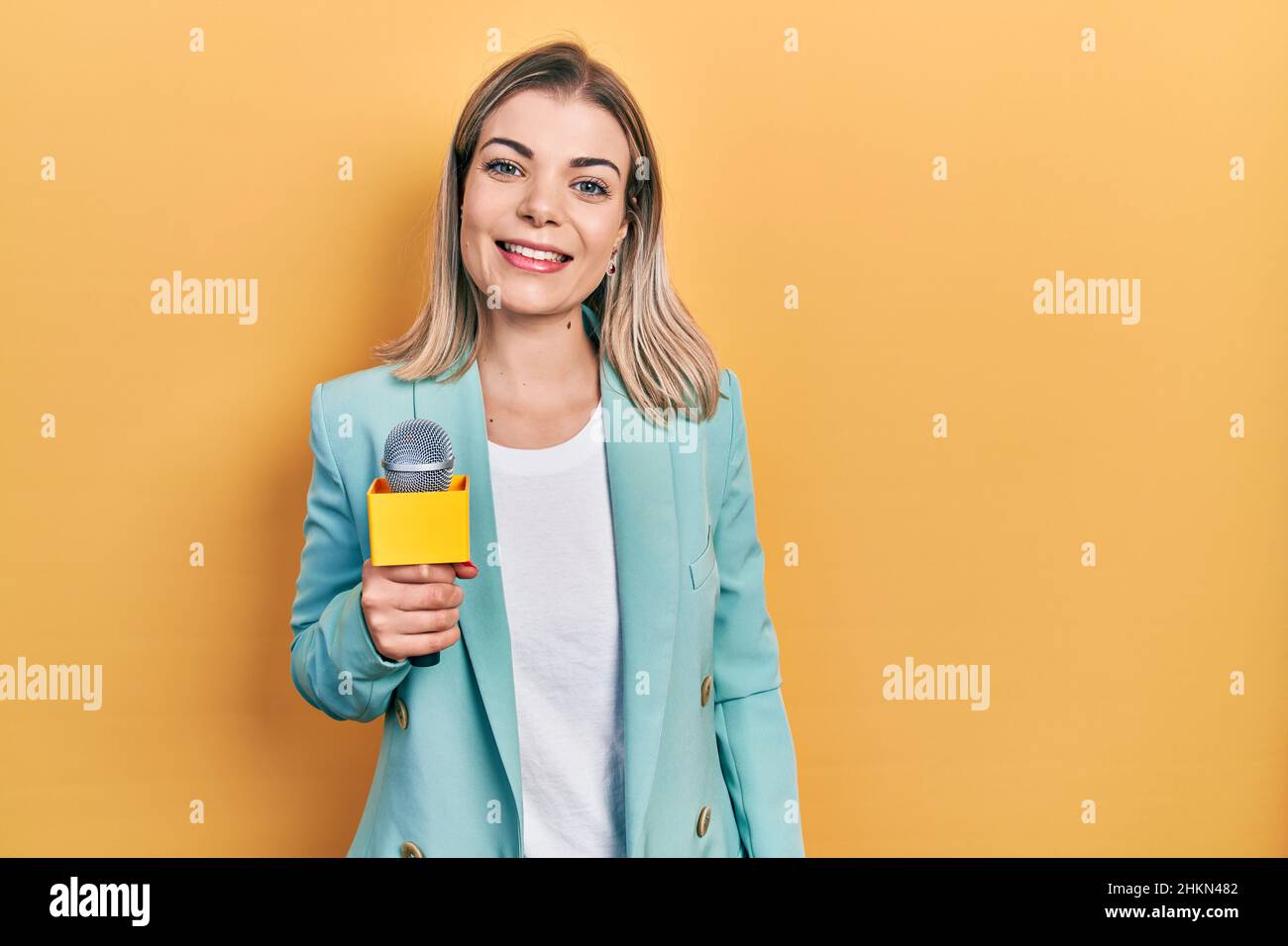 Beautiful caucasian woman holding reporter microphone looking positive ...
