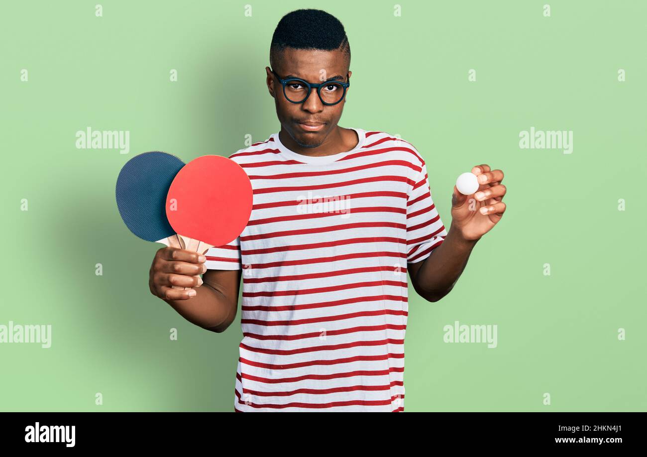 Young african american man holding red ping pong rackets and ball ...