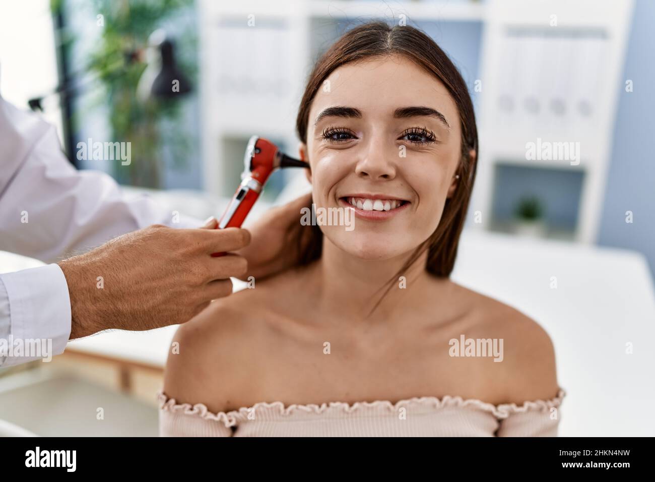 Man and woman wearing doctor uniform auscultating ear using otoscope at ...