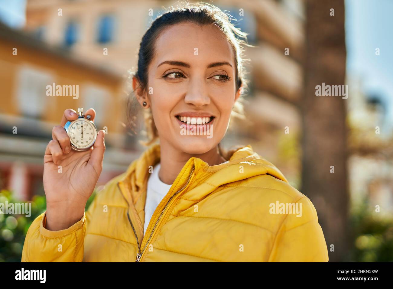 Young hispanic girl smiling happy holding stopwatch at the city Stock ...