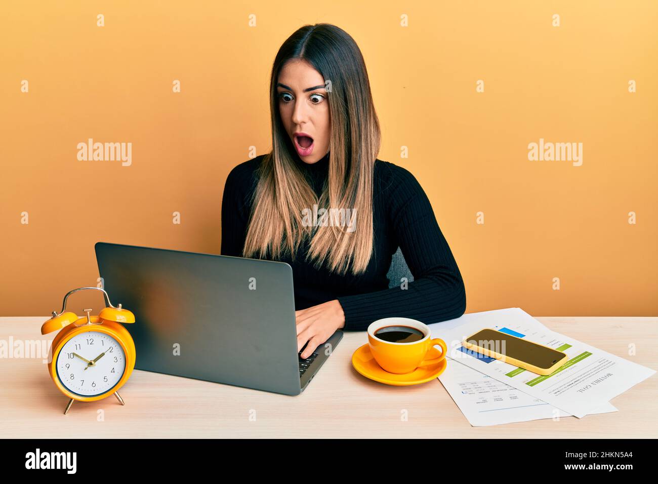 Young hispanic woman working at the office with laptop afraid and ...