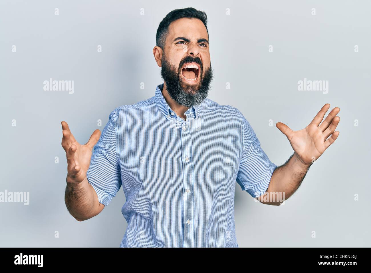 Young hispanic man wearing casual clothes crazy and mad shouting and ...