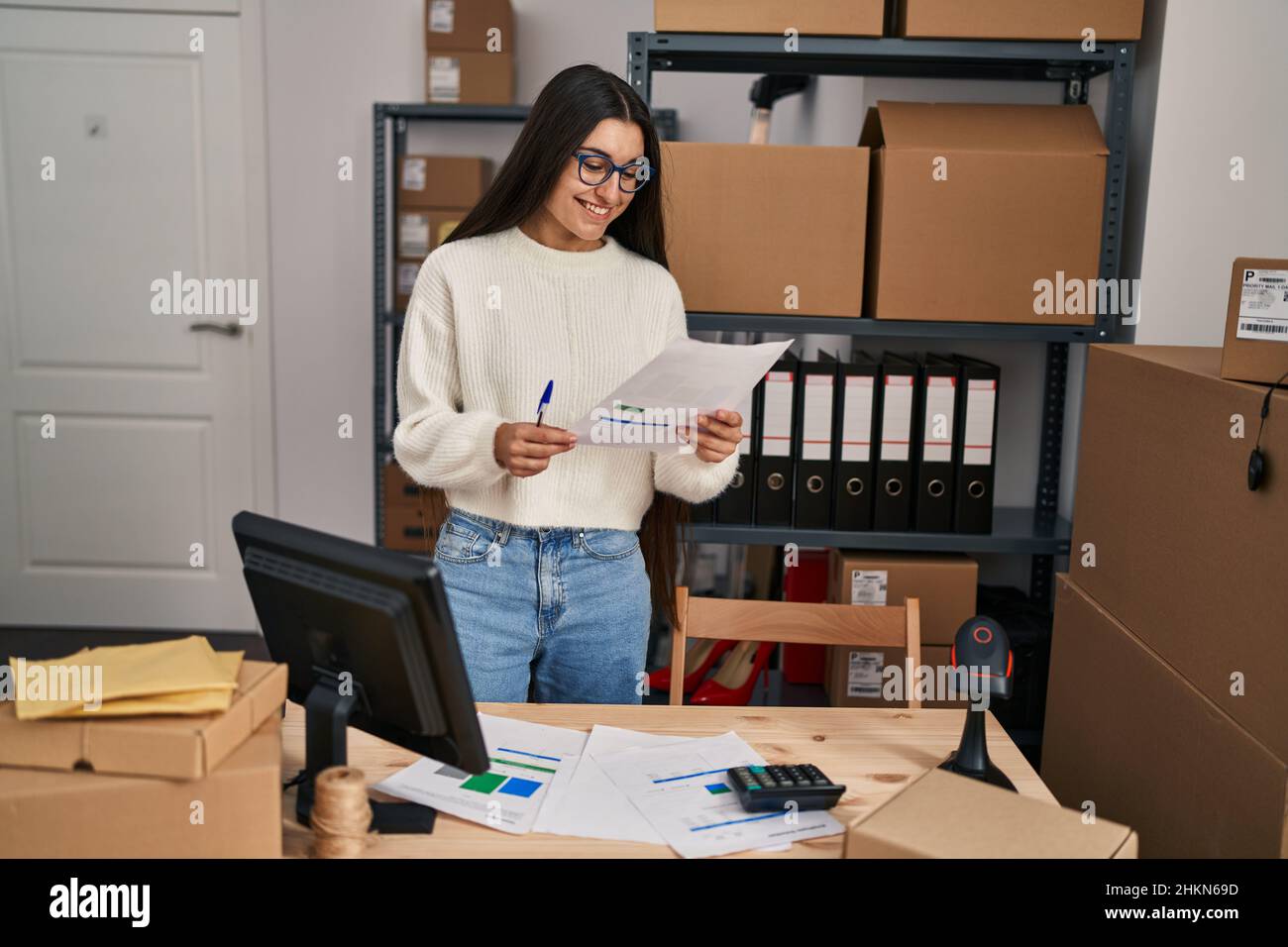 Young hispanic woman ecommerce business worker read document at office ...