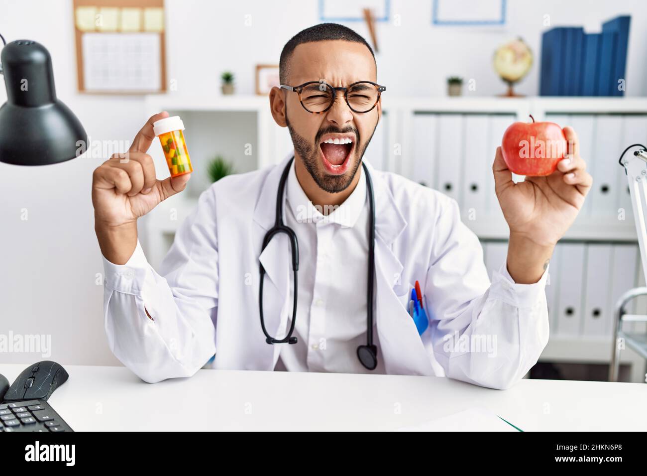 African american doctor man holding prescription pills and fresh apple ...