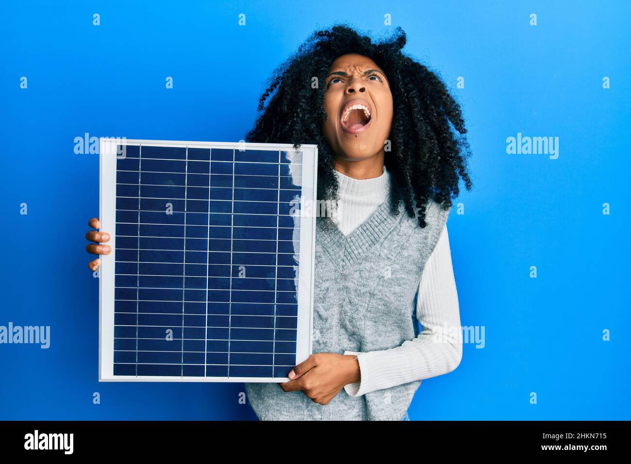 African american woman with afro hair holding photovoltaic solar panel ...