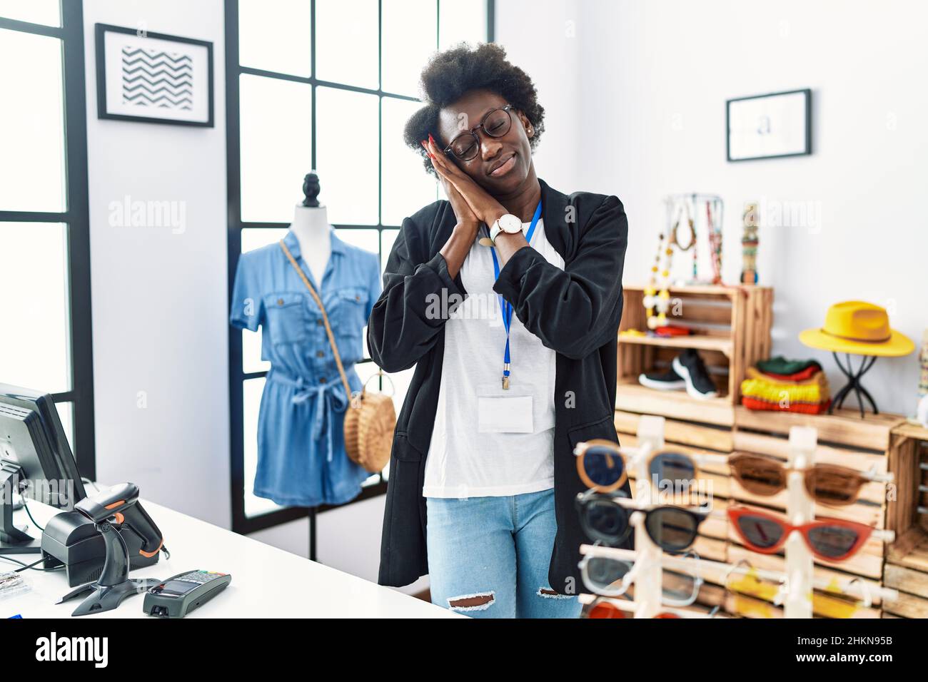 African young woman working as manager at retail boutique sleeping tired dreaming and posing ...