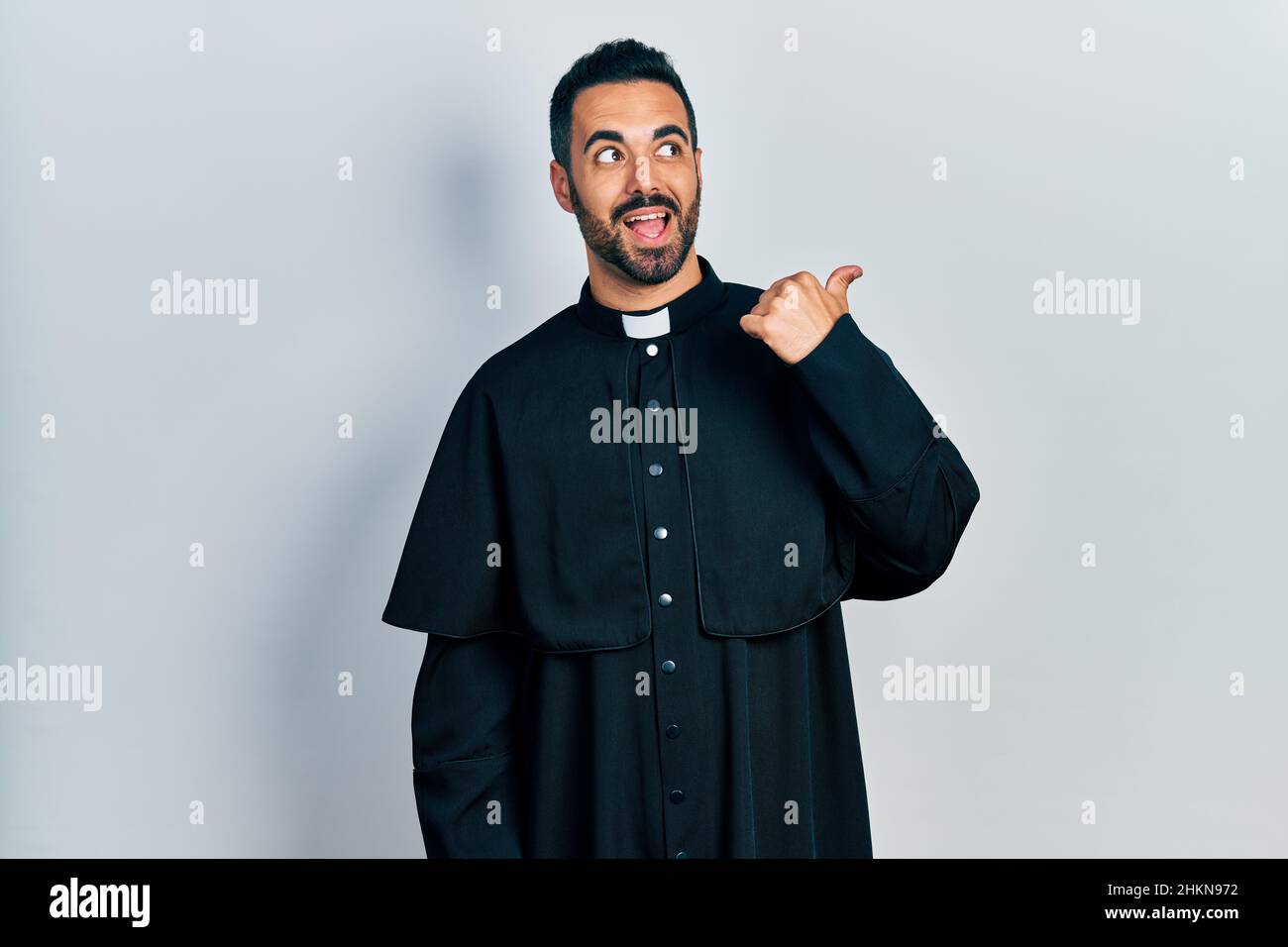 Handsome hispanic man with beard wearing catholic priest robe smiling ...