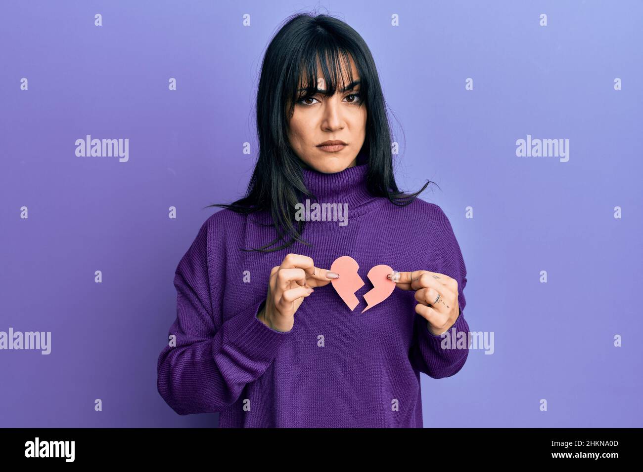 Young brunette woman with bangs holding broken heart paper shape ...