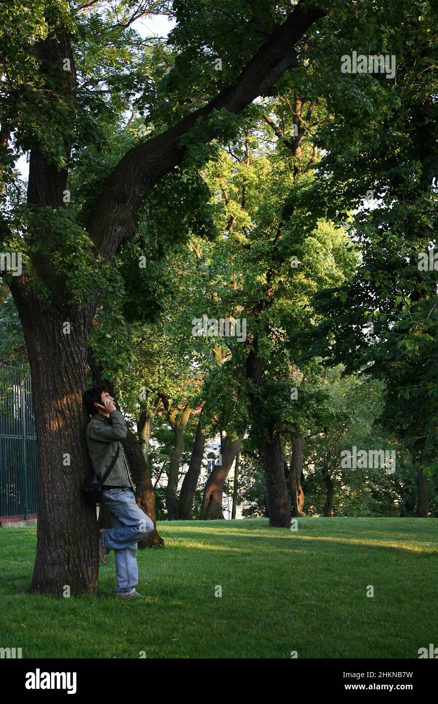 A man stands by a tree and talks on the phone Stock Photo - Alamy