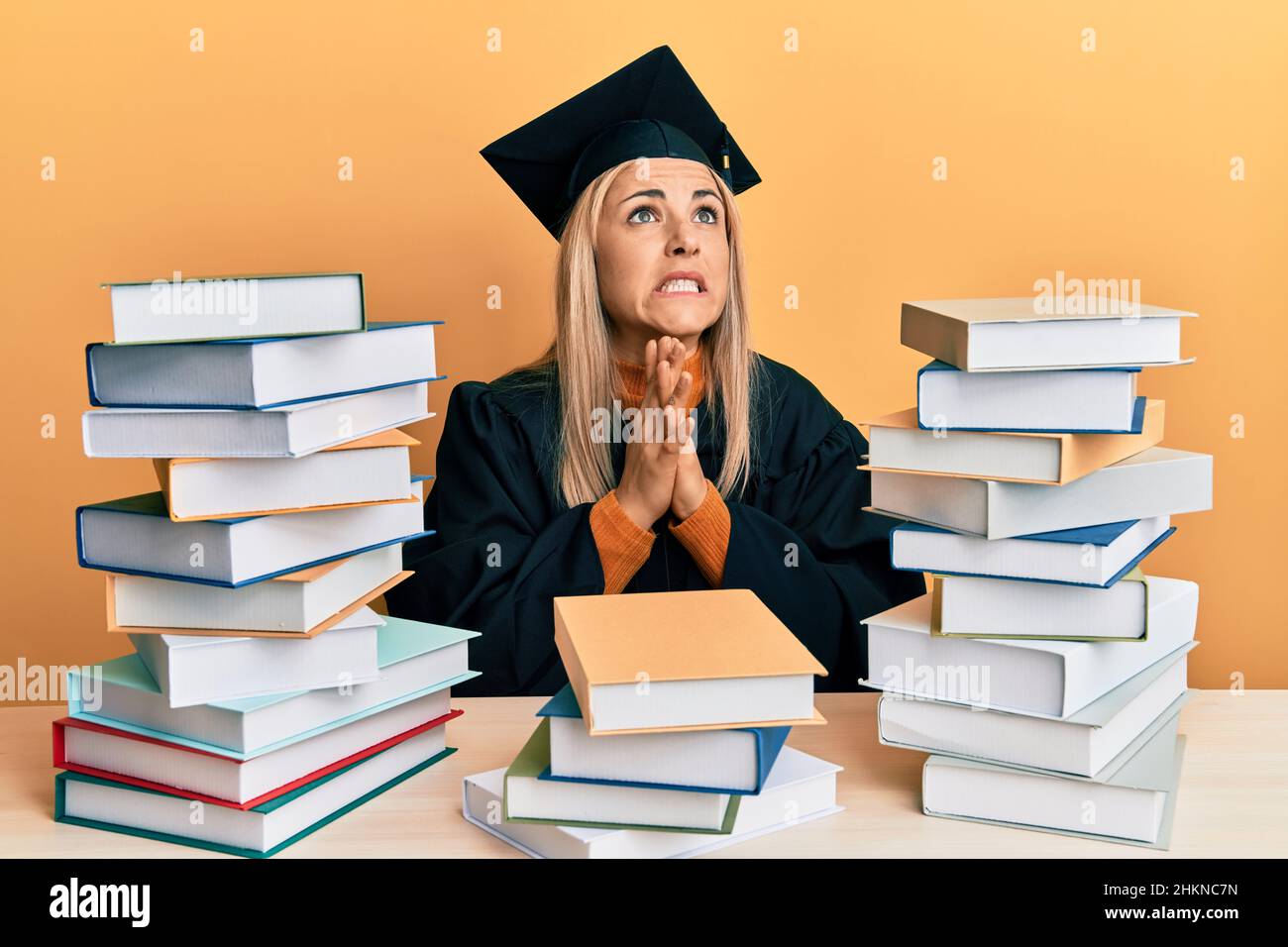 Young caucasian woman wearing graduation ceremony robe sitting on the ...