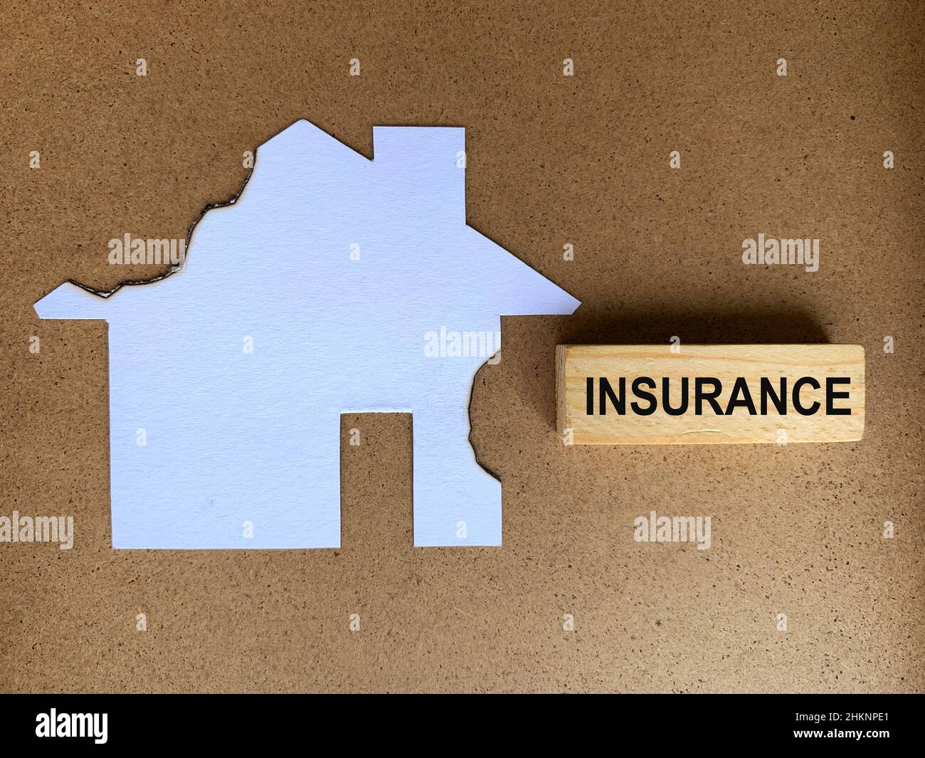 Insurance text on wooden block with burnt model house background ...