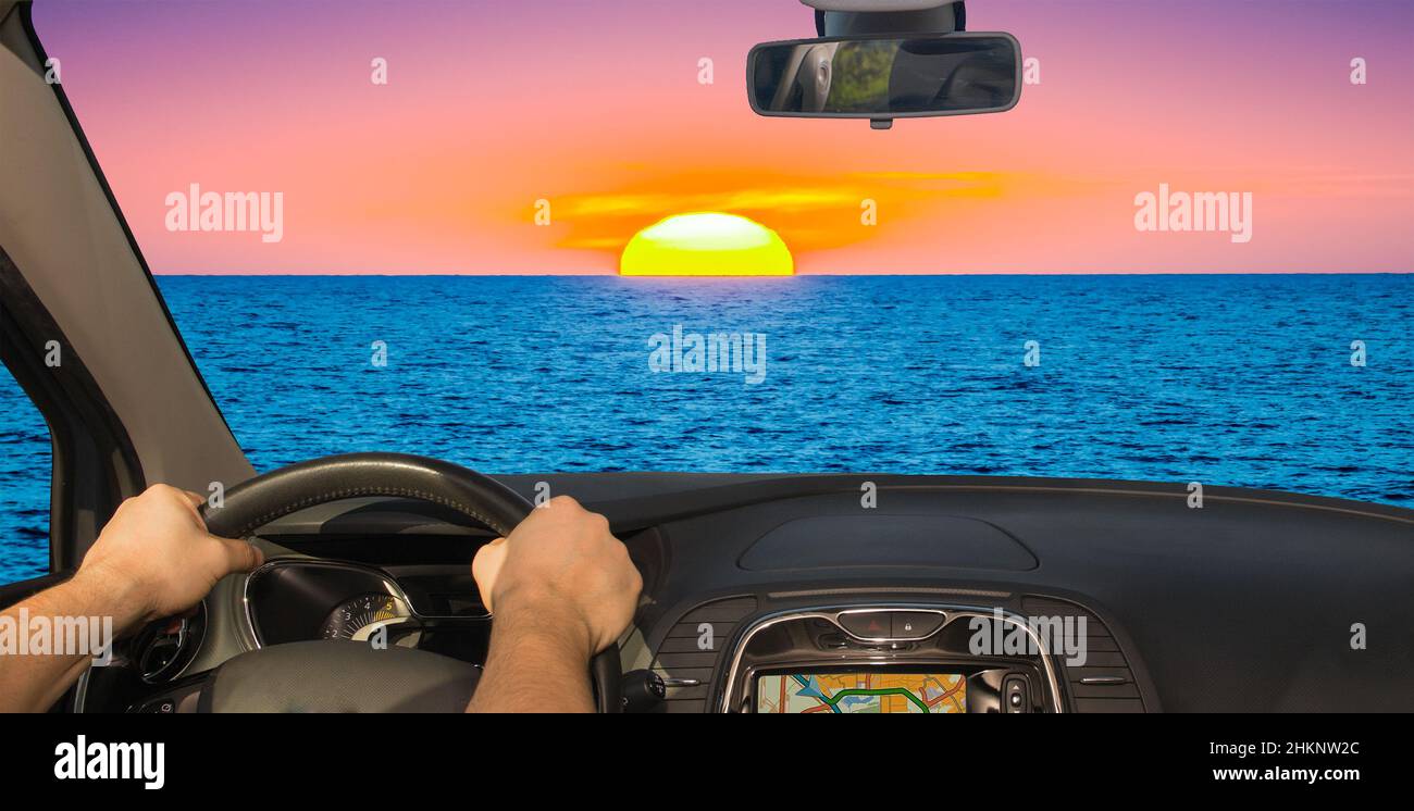 Driving a car towards a beautiful sunset by the mediterranean sea ...