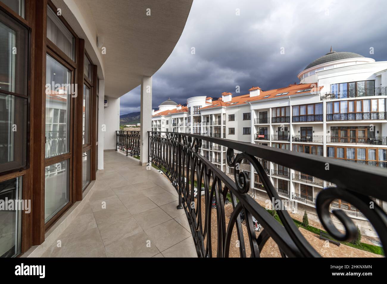 A wide curved balcony of a multi-storey building with metal black ...
