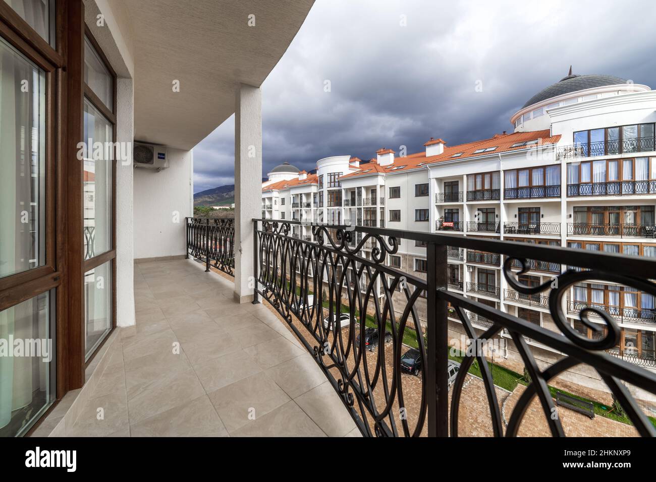 A wide curved balcony of a multi-storey building with metal black ...
