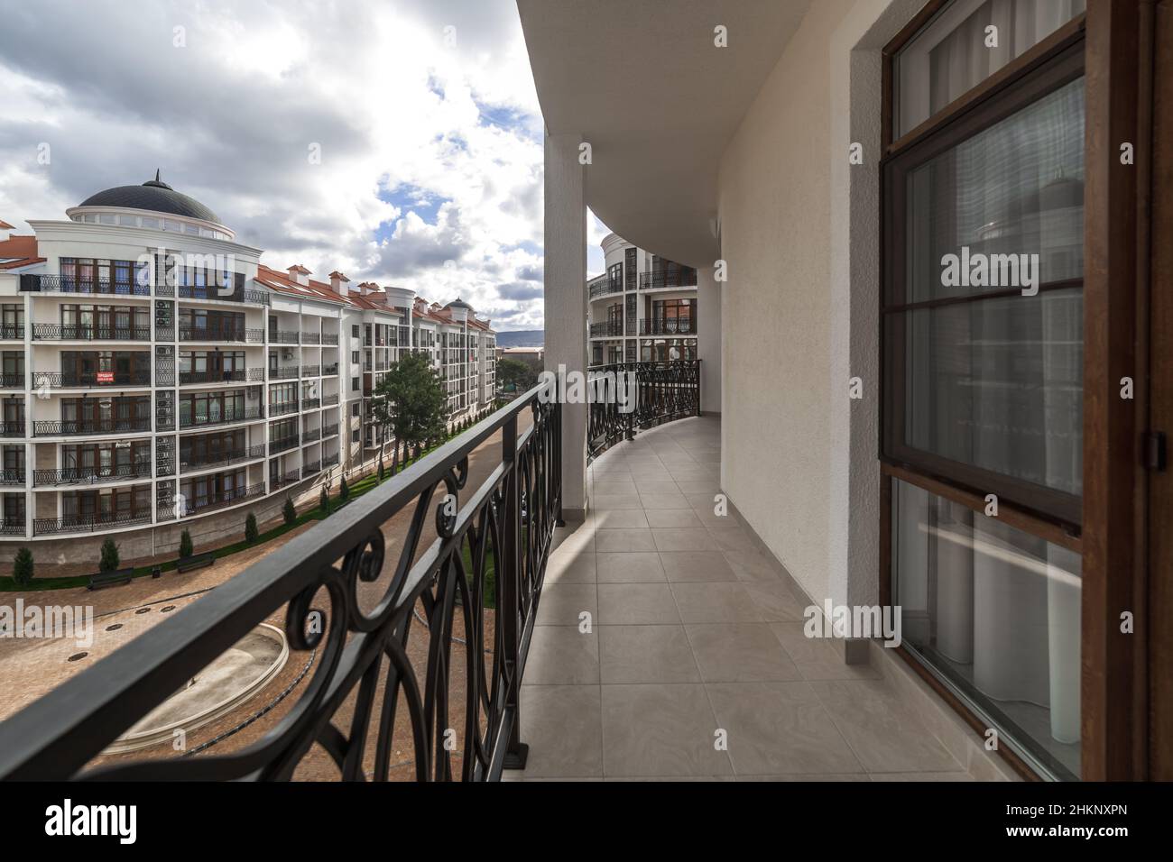 A wide curved balcony of a multi-storey building with metal black ...
